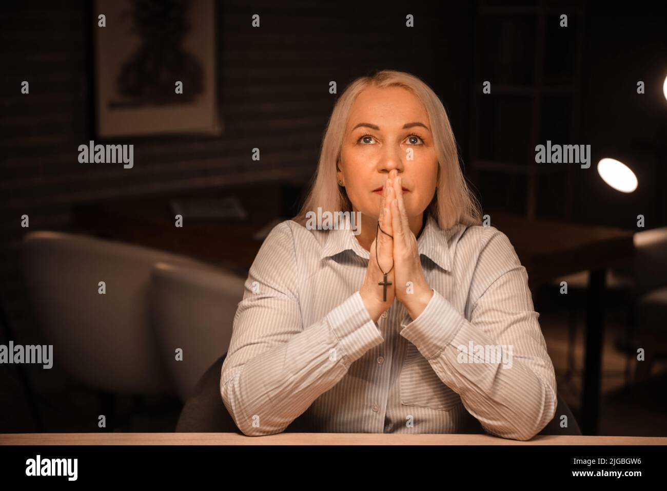 Religious mature woman praying in dark room Stock Photo - Alamy