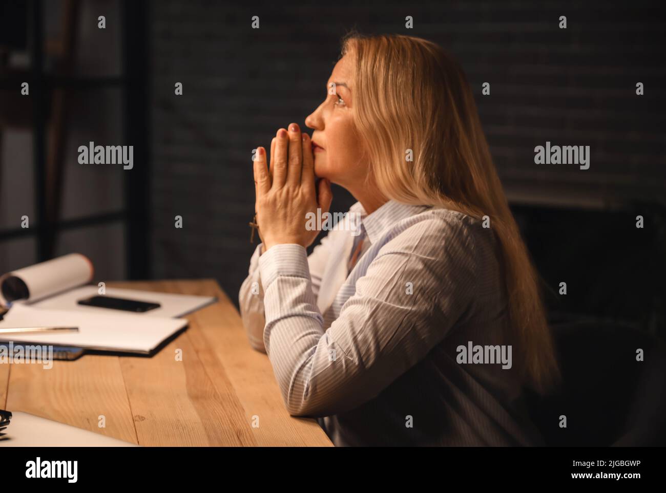 Religious mature woman praying in dark room Stock Photo - Alamy