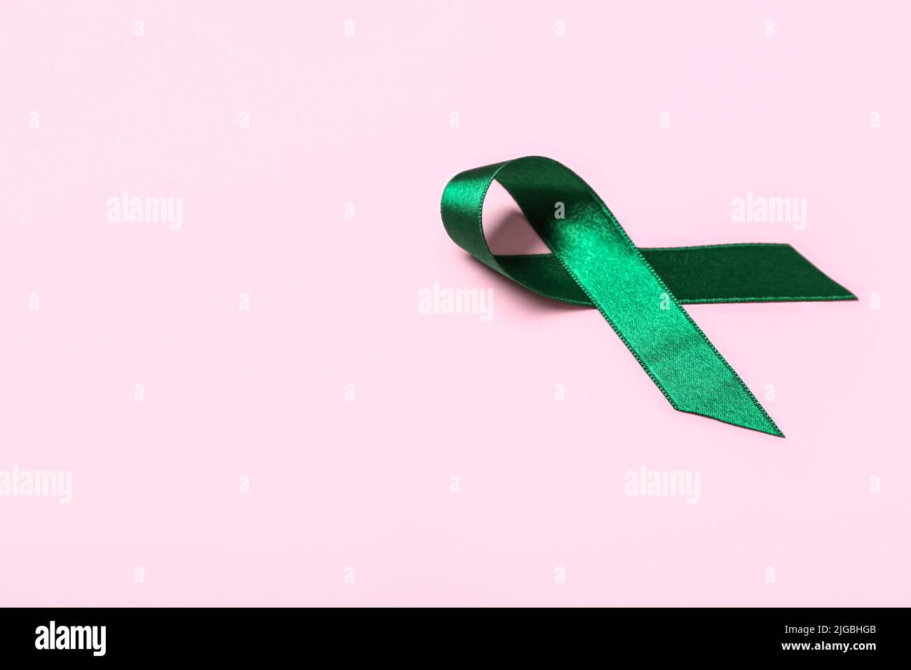 Green ribbon on pink background. Liver cancer concept Stock Photo - Alamy