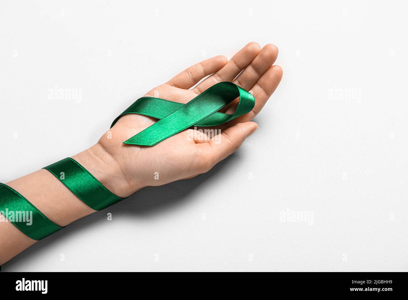 Hand with green ribbon on light background. Liver cancer concept Stock ...
