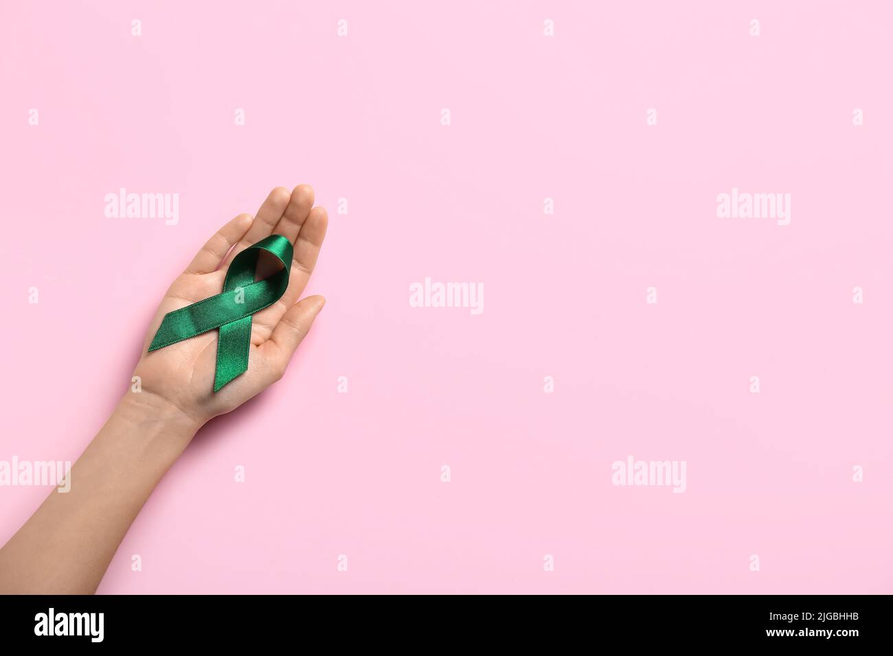 Hand with green ribbon on pink background. Liver cancer concept Stock ...