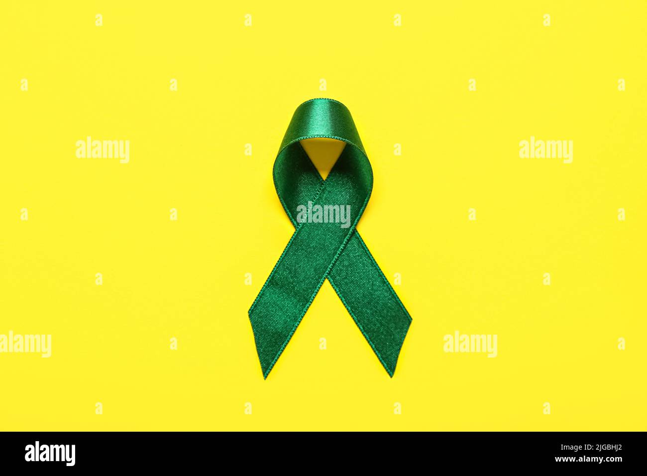 Green ribbon on yellow background. Liver cancer concept Stock Photo - Alamy
