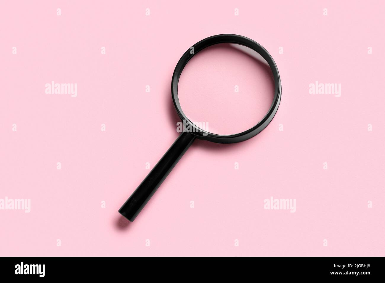 Magnifying glass on pink background Stock Photo - Alamy