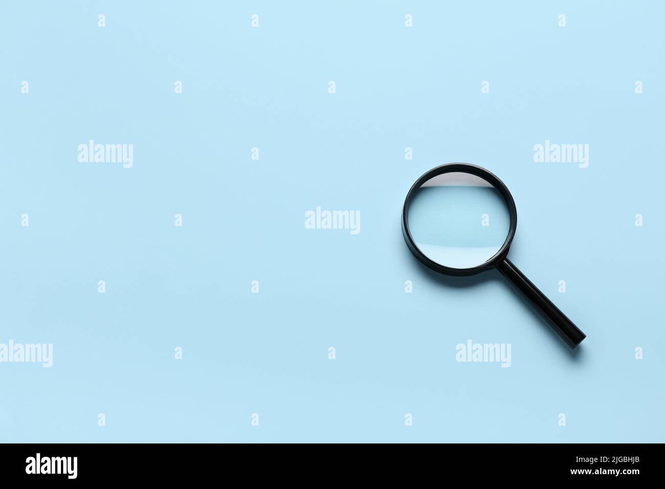 Magnifying glass on light blue background Stock Photo - Alamy