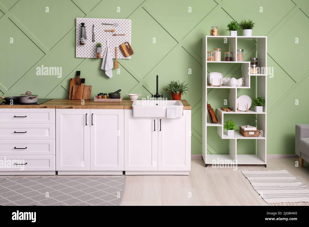 Interior of stylish kitchen with white counters, pegboard and shelving ...