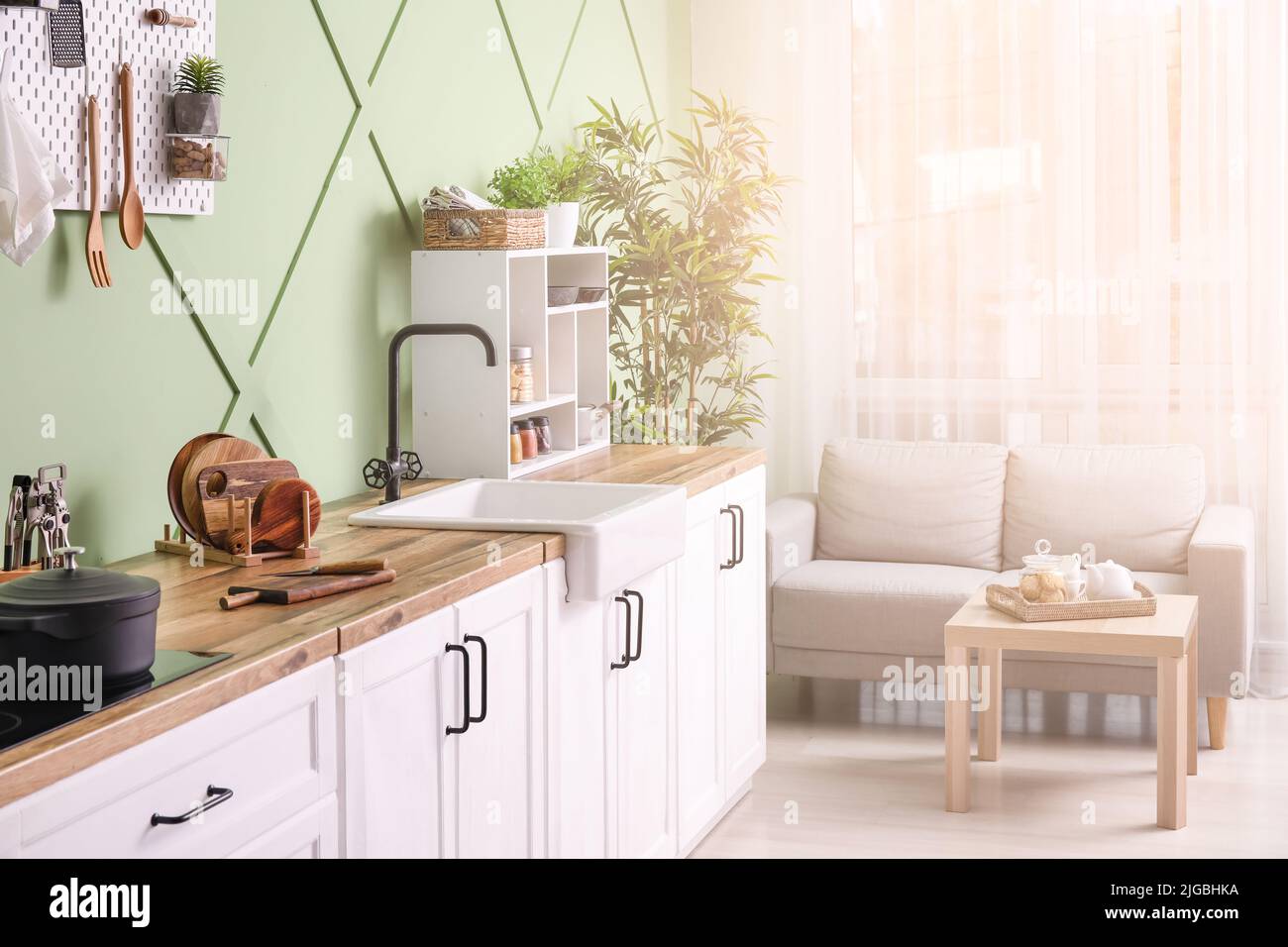 Interior of stylish kitchen with white counters, sofa and window Stock ...