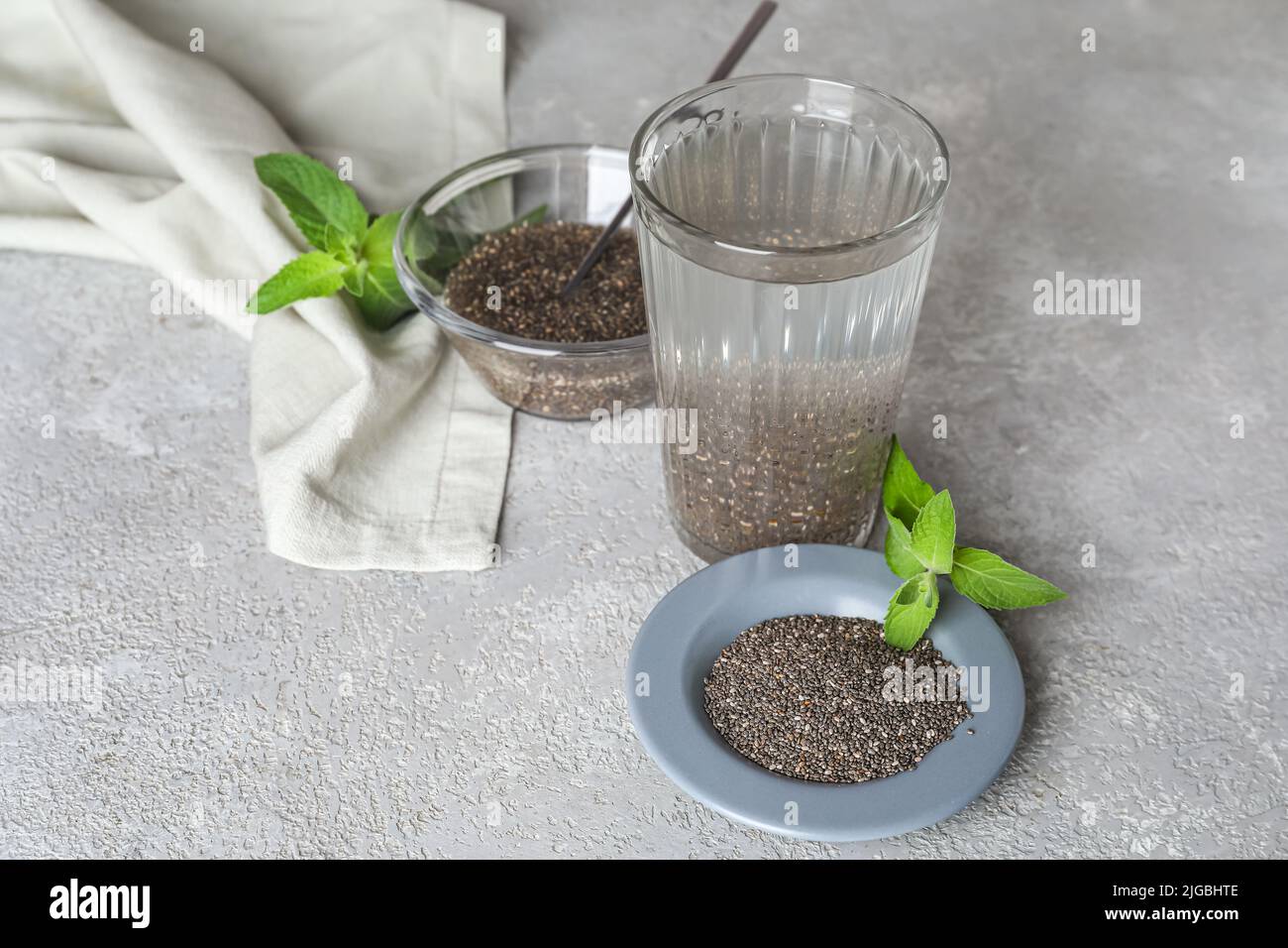 Glass of water and plate with chia seeds on light background Stock ...