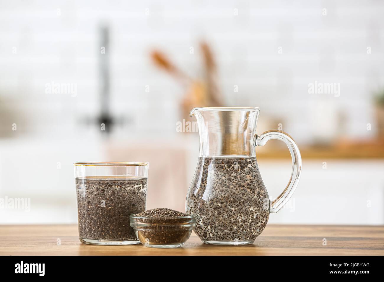 Glass of water, jug and bowl with chia seeds on table in kitchen Stock ...