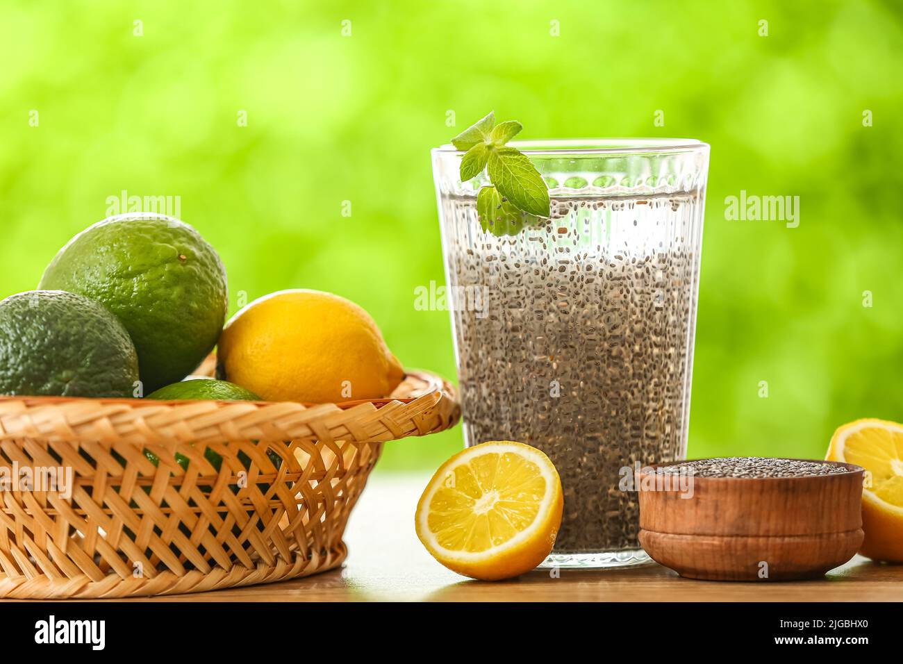 Glass of water with chia seeds, basket and citrus fruits on table ...