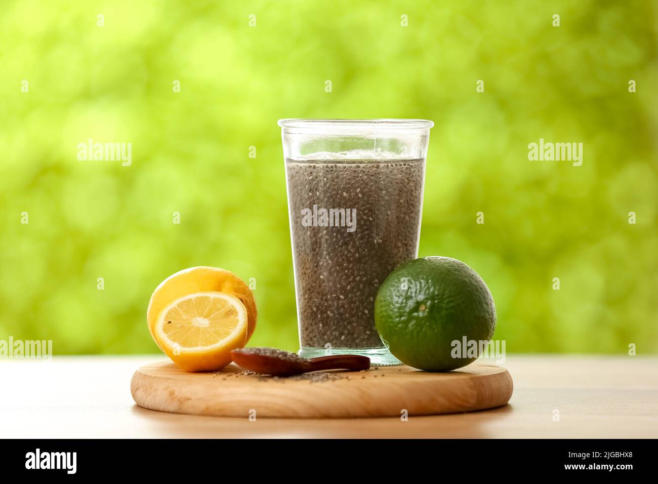 Board, glass of water with chia seeds, citrus fruits and spoon on table ...