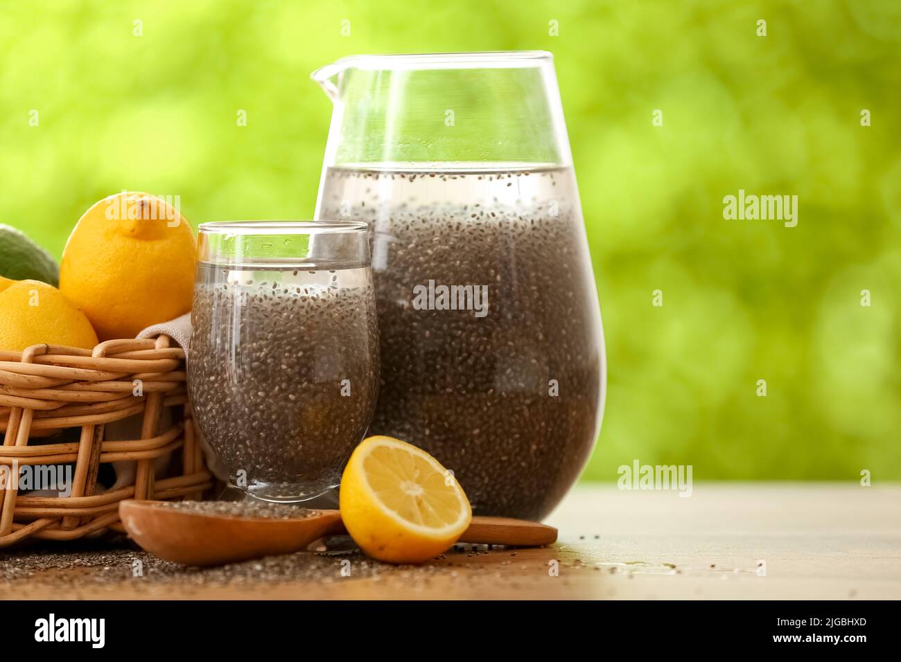 Glass of water with chia seeds, jug, citrus fruits and spoon on table ...