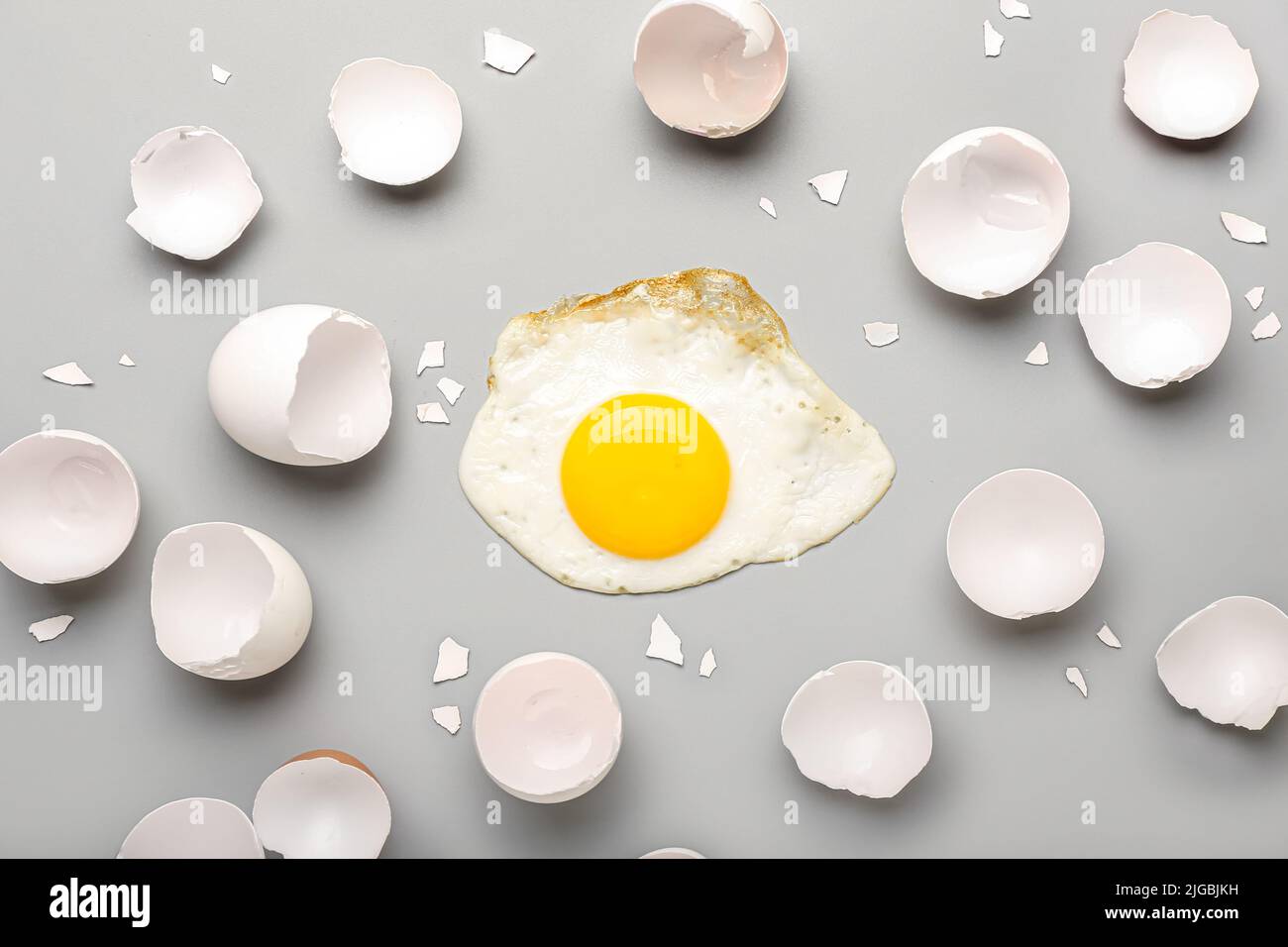 Composition with tasty fried egg and shells on light background Stock ...