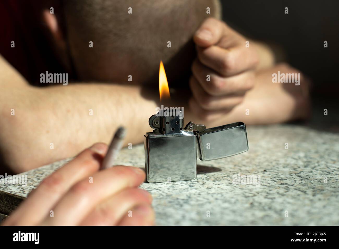 Gasoline lighter burns on table. Fire in background of sleeping guy ...