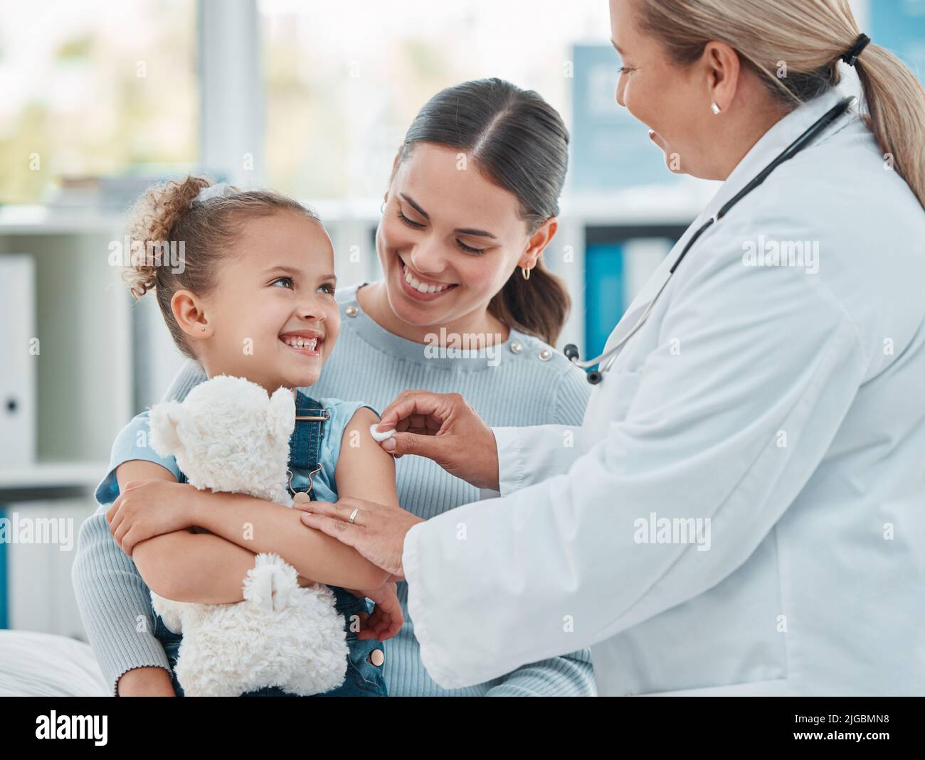 Shes not afraid to get her routine vaccine. a doctor using a cotton ...