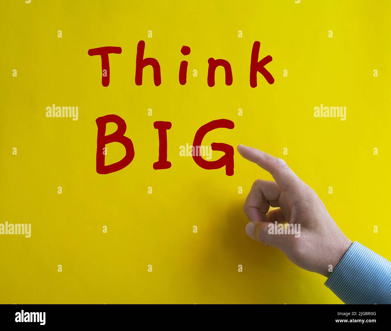 Hand pointing Think Big text on yellow cover background. Thinking ...