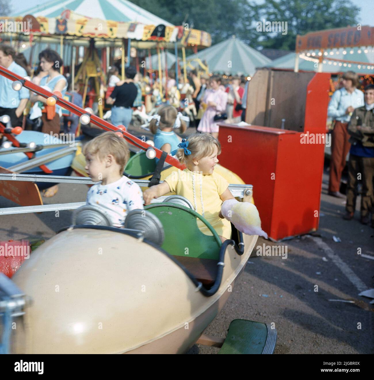 1970s, historical, children on an amusement ride at a fairground, a young girl sitting on the ...