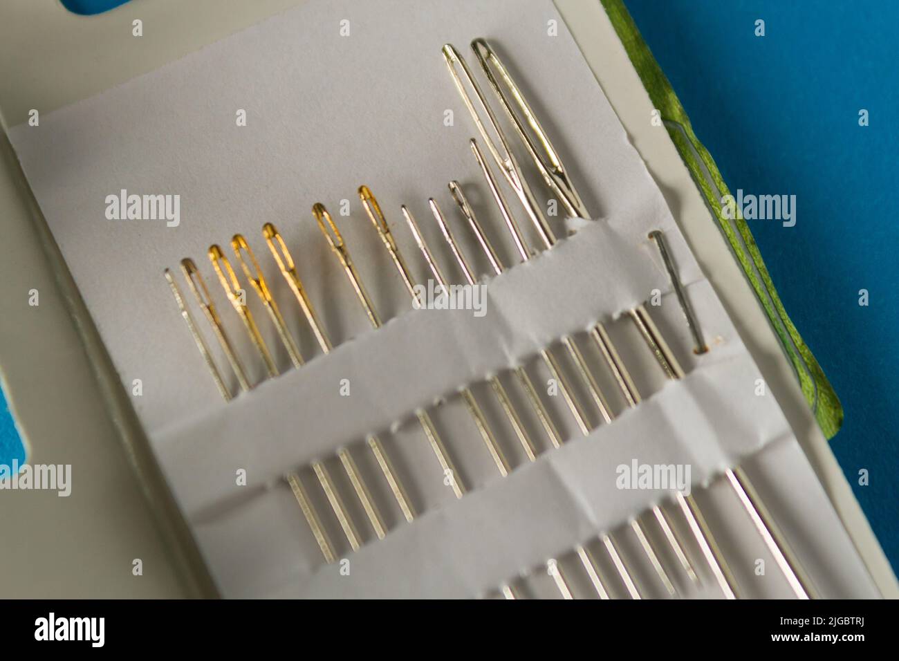 A set of needles for sewing. Blue background Stock Photo - Alamy