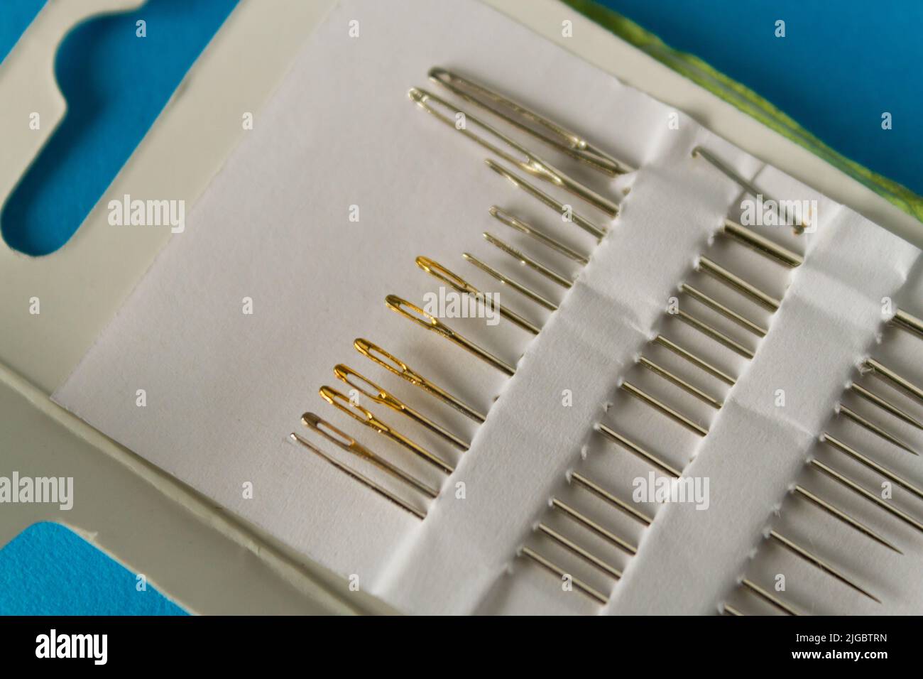 A set of needles for sewing. Blue background Stock Photo - Alamy