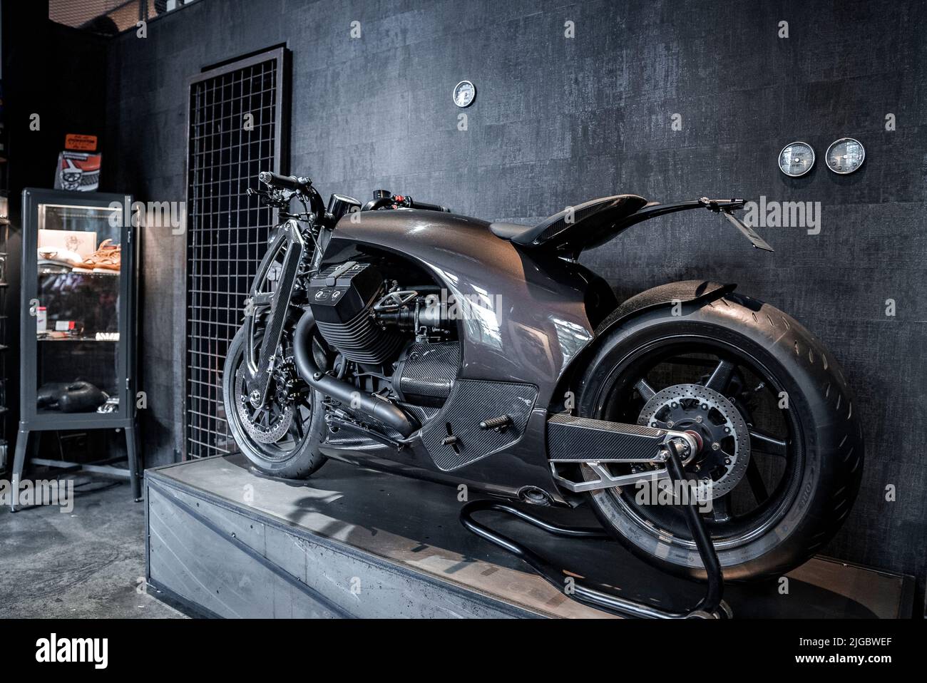 Modern motorcycle on platform against gray wall by rack in One sixty ...