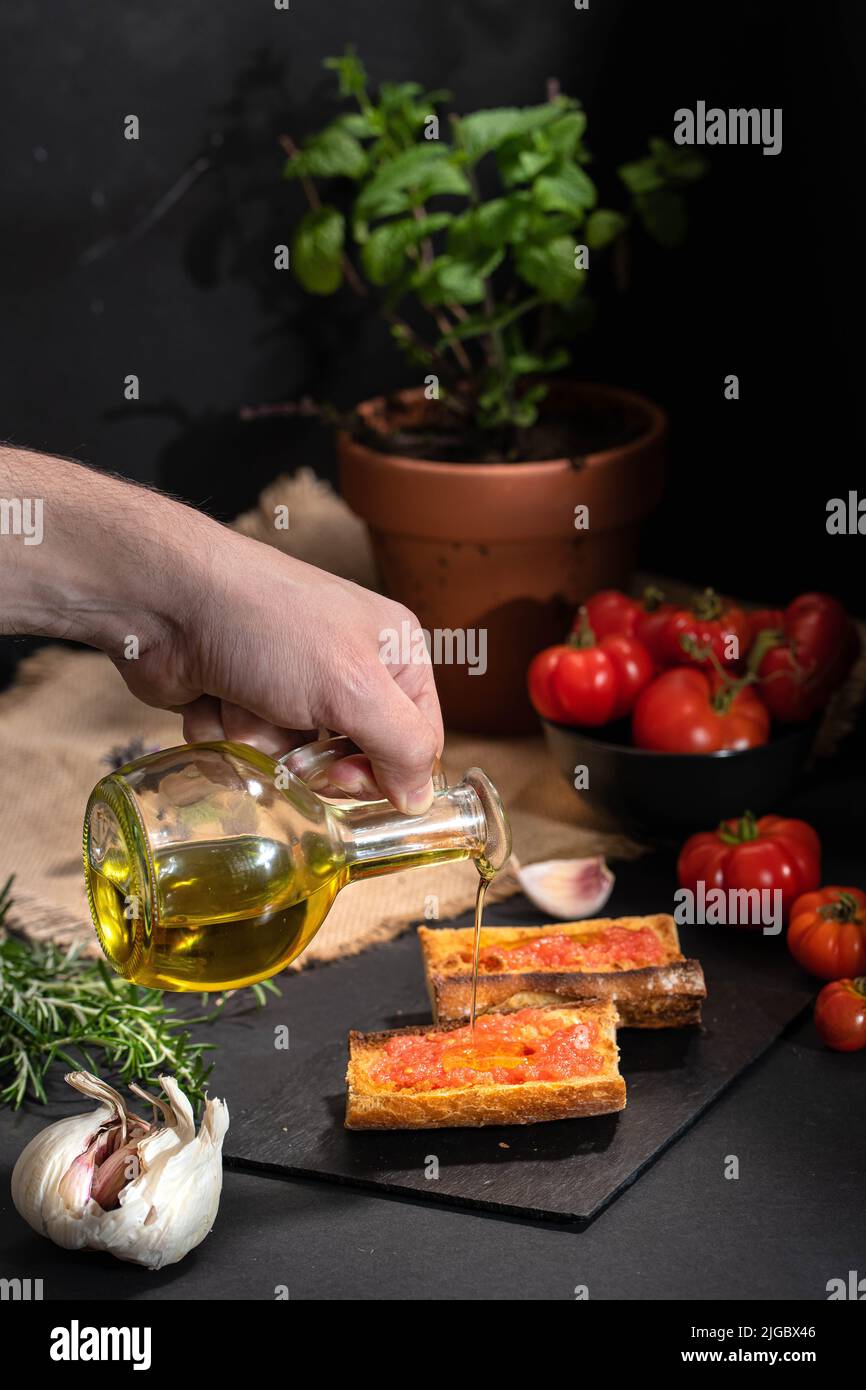 Pouring olive oil on the top of traditional Spanish appetiser - "Pan ...