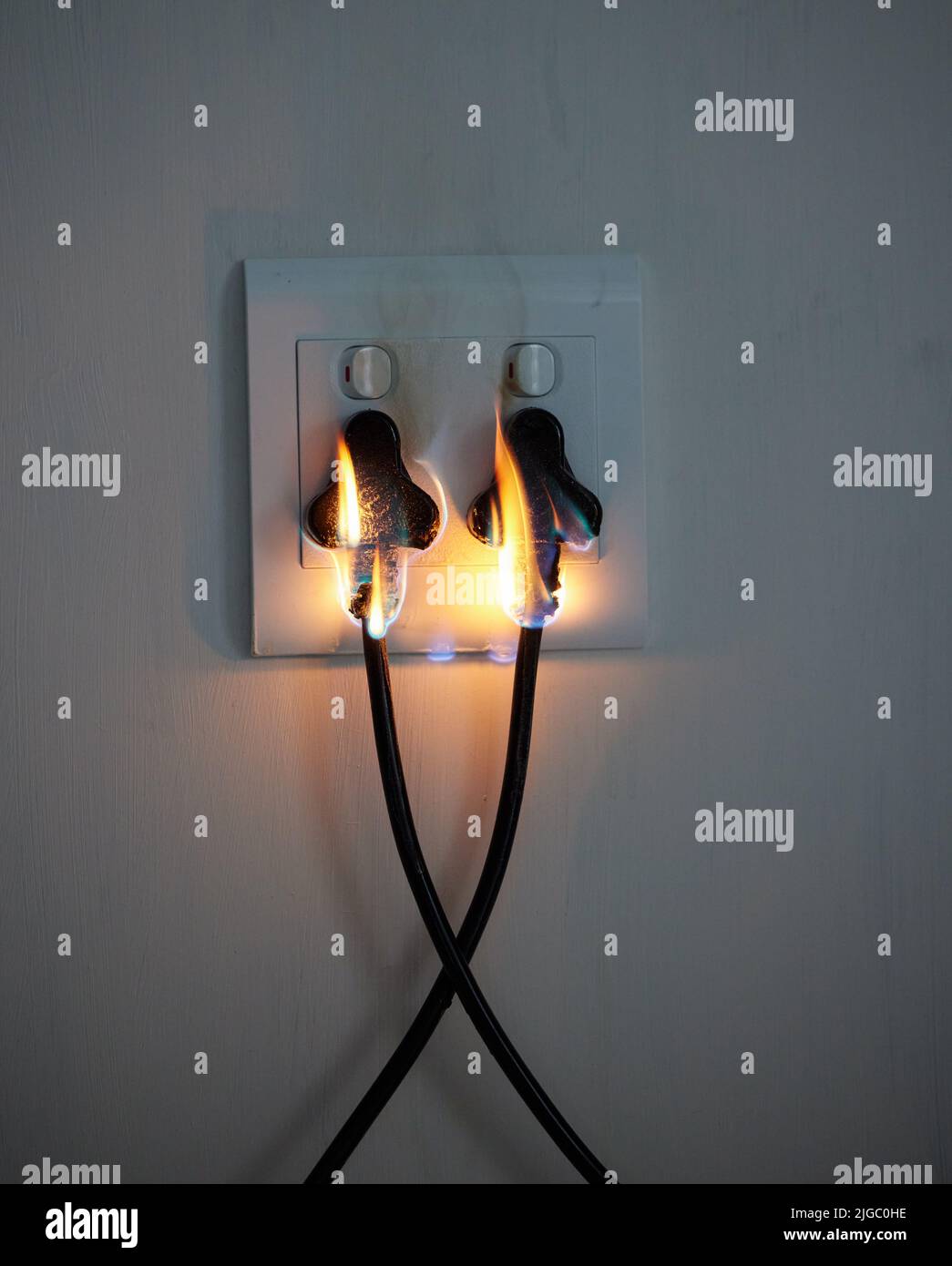 Are you covered. two plugs in a wall socket catching fire Stock Photo ...
