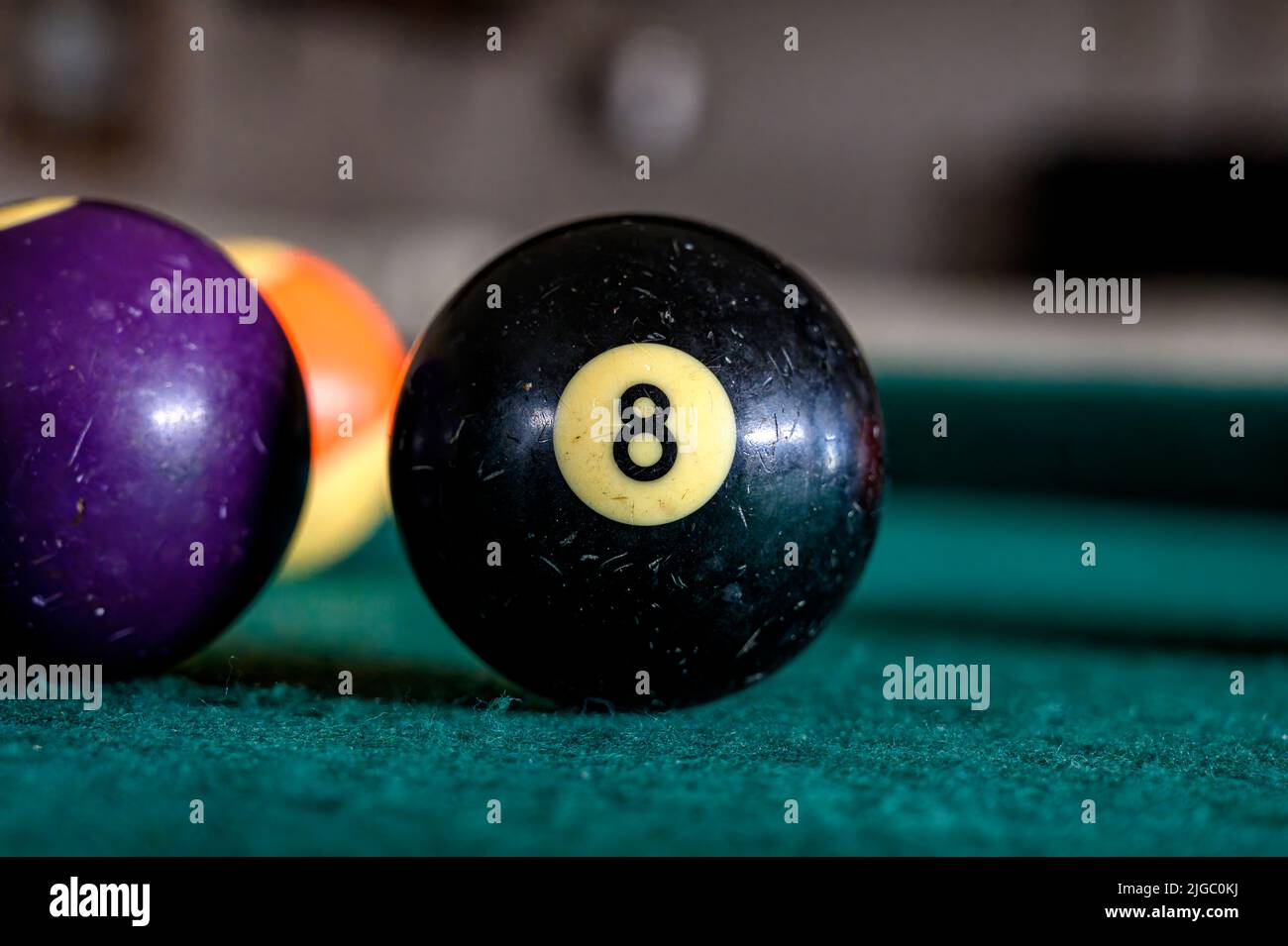 Black billiard ball with the number 8 on a green billiard table with ...