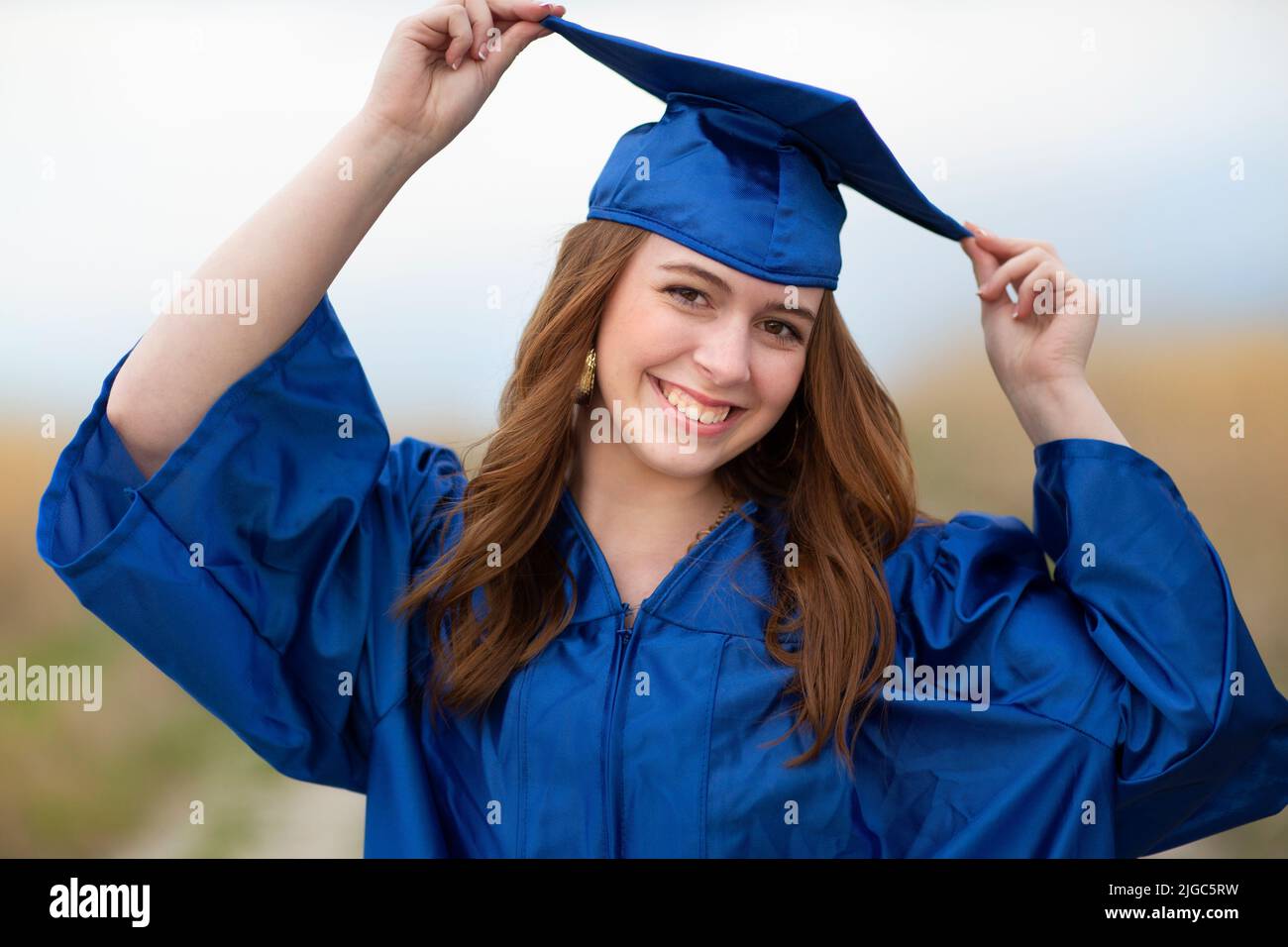 A pretty high school senior girl holding her cap with her graduation ...