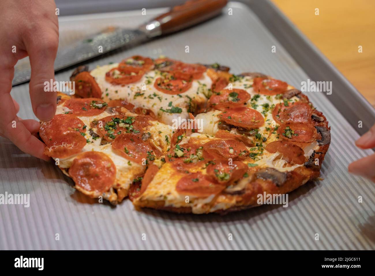 A hand taking a homemade pepperoni pizza Stock Photo - Alamy