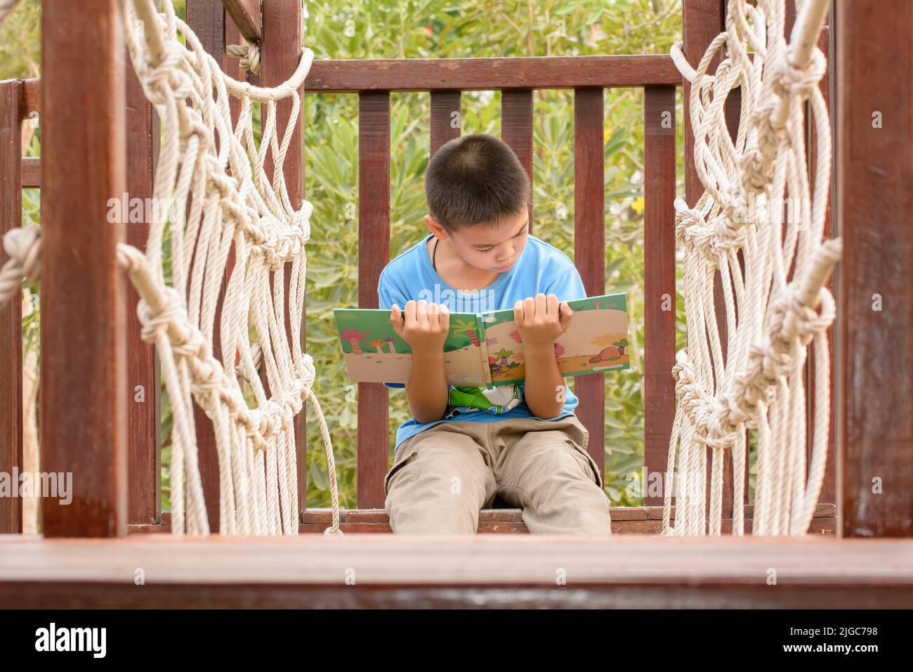 The view of a boy child reading a book in the children's play park ...