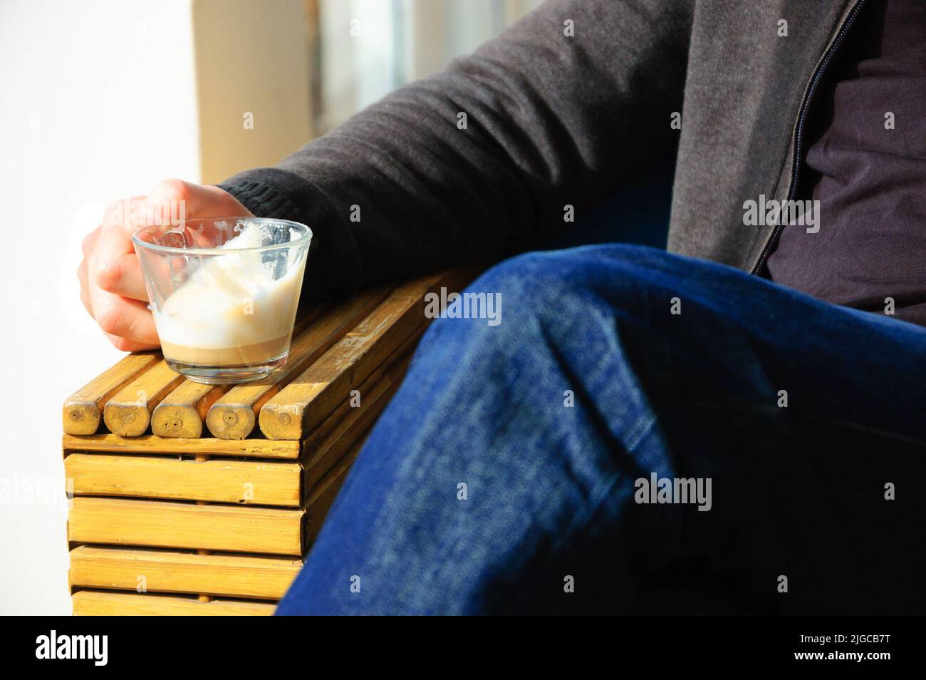 Close up male hands holding coffee while sitting on rustic sofa at home ...