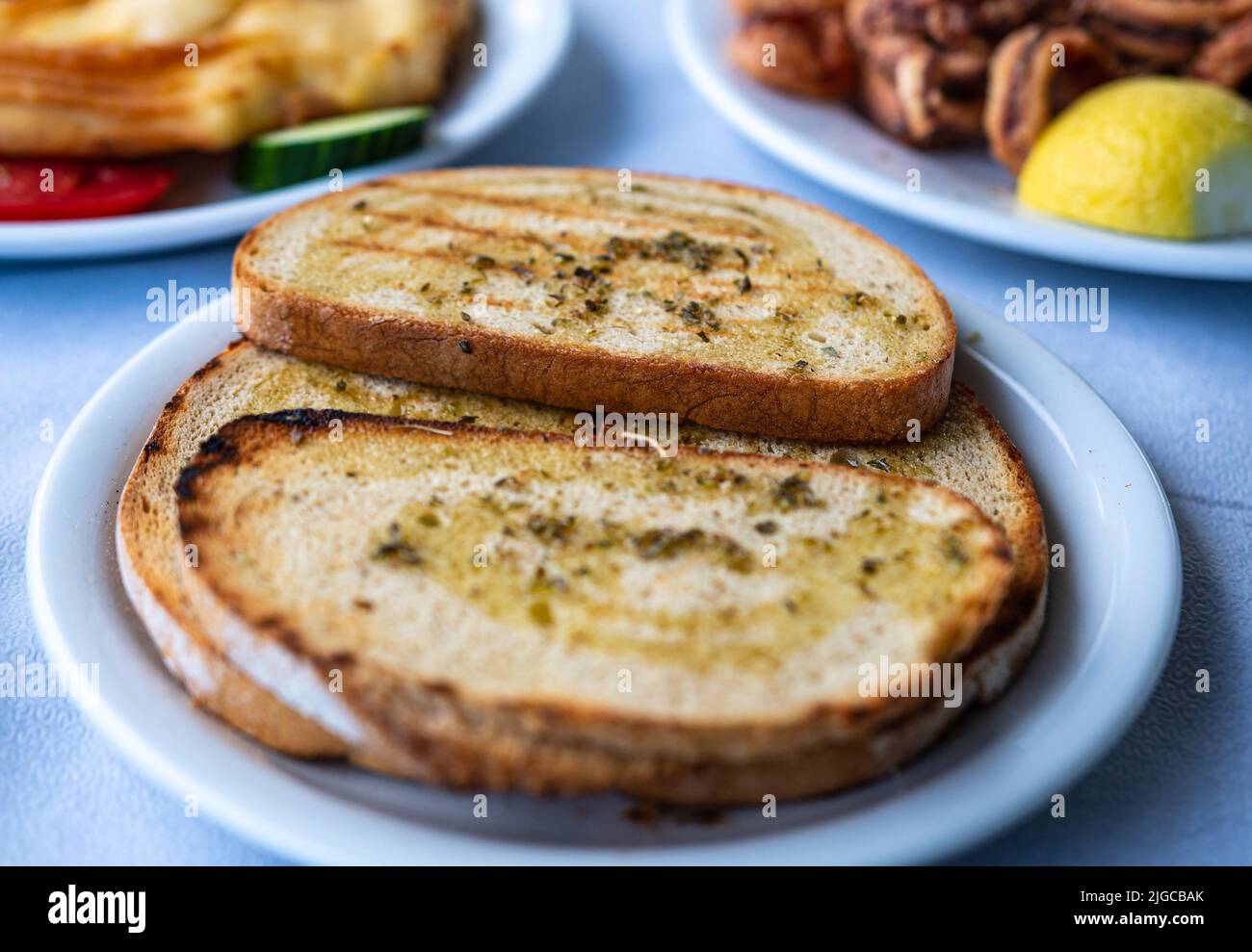 Crisp, toasted bread with drops of olive oil and herbs on a plate ...