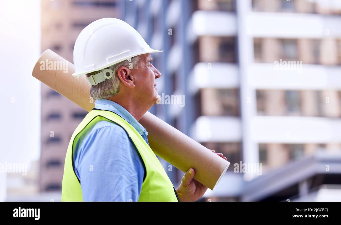 Planning ahead. a handsome mature male construction worker carrying ...
