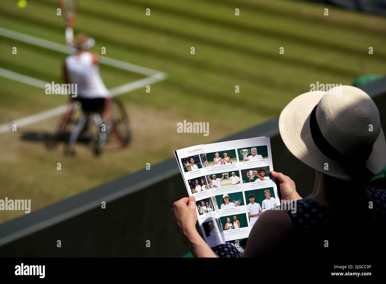 A spectator reads a programme on day thirteen of the 2022 Wimbledon ...