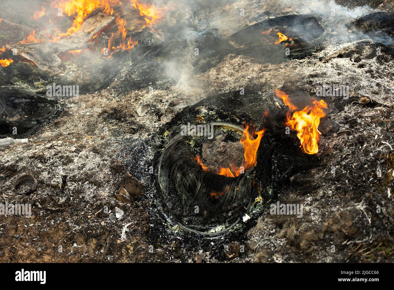 Burning wheels in landfill. Details of fire. Ashes and smoke ...