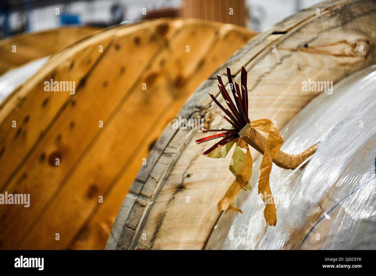 Wooden coil with thick copper wire. Part of the wire sticks out in a ...