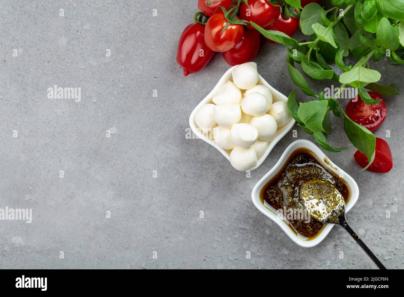 Mozzarella cheese with basil, pesto sauce, and tomatoes on an old stone ...