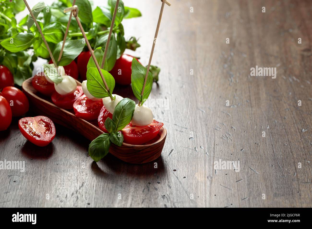 Mozzarella with basil and tomatoes on an old wooden table. Traditional ...