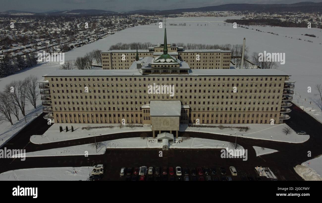 An aerial view of a huge building surrounded by white snow in a rural ...
