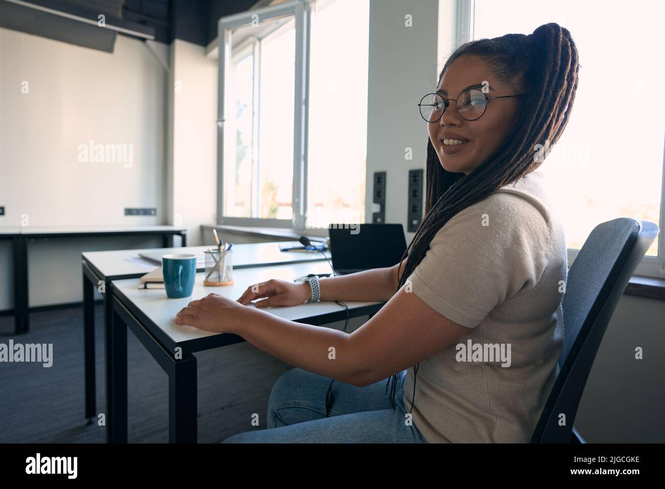 Joyful corporate employee posing for camera in workplace Stock Photo ...