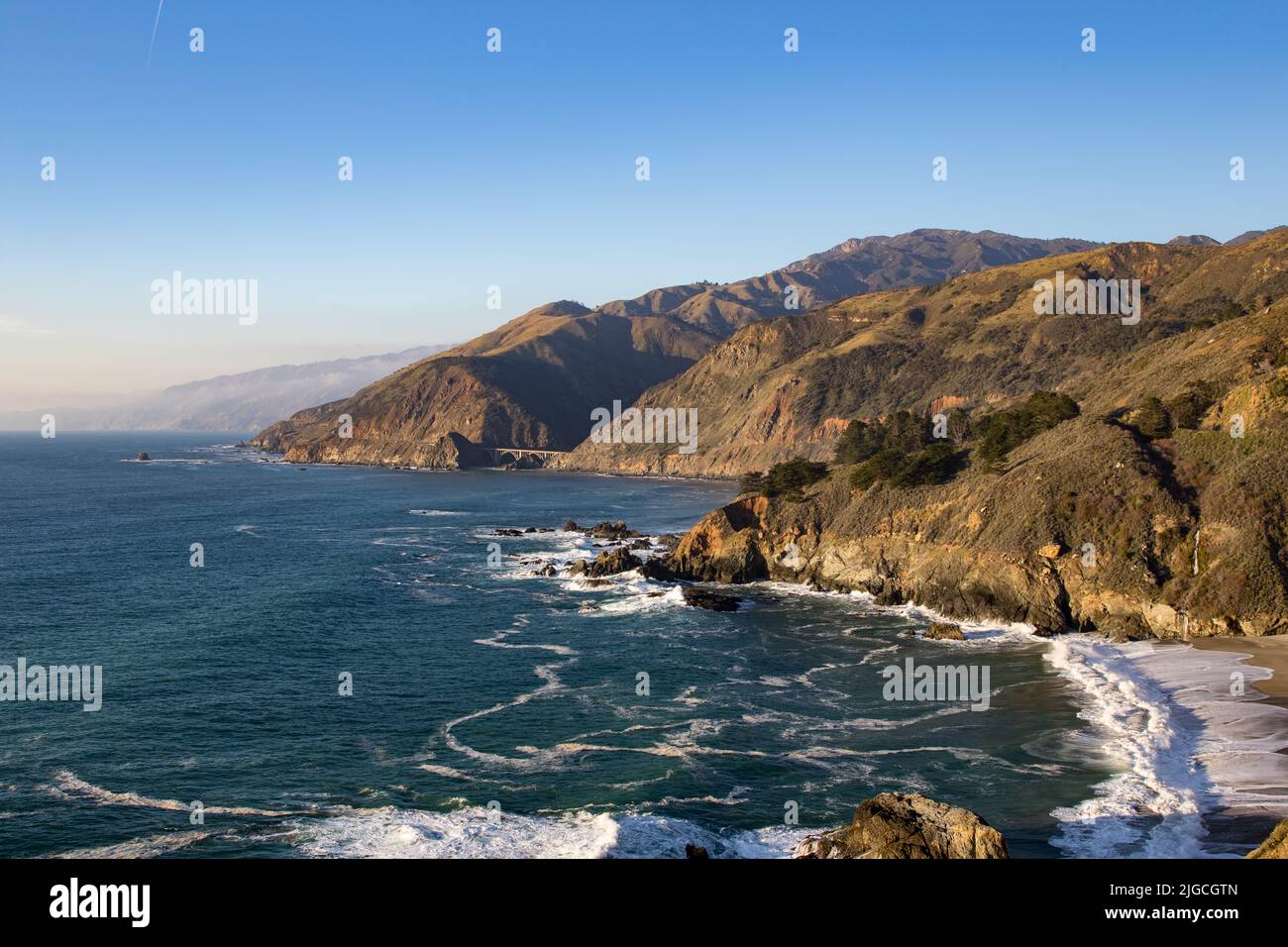 An aerial view of ocean waves crashing against coastal mountains ...
