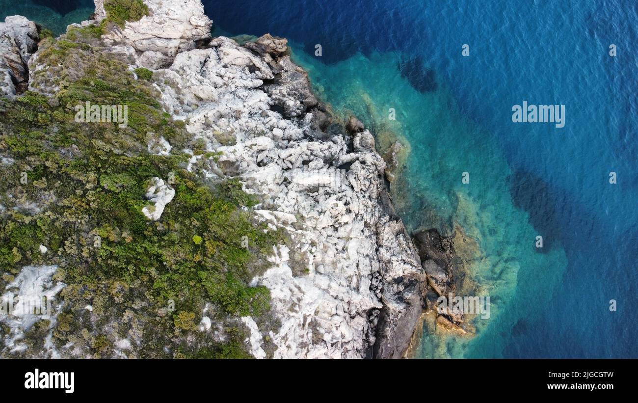 An aerial top view of a turquoise sea near a rocky coast covered with ...