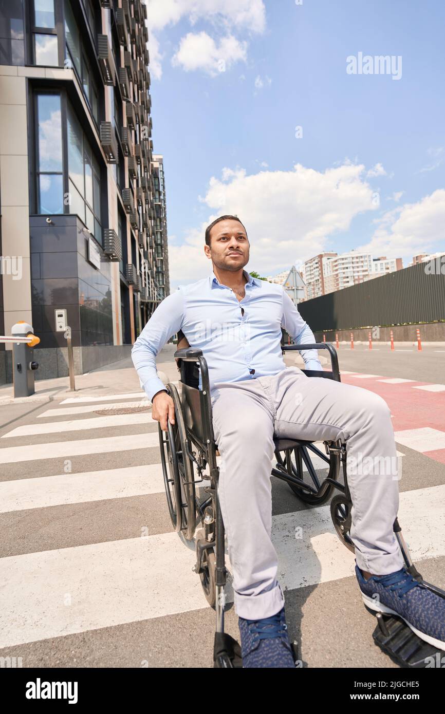 Disabled man seated in wheelchair crossing crosswalk Stock Photo - Alamy