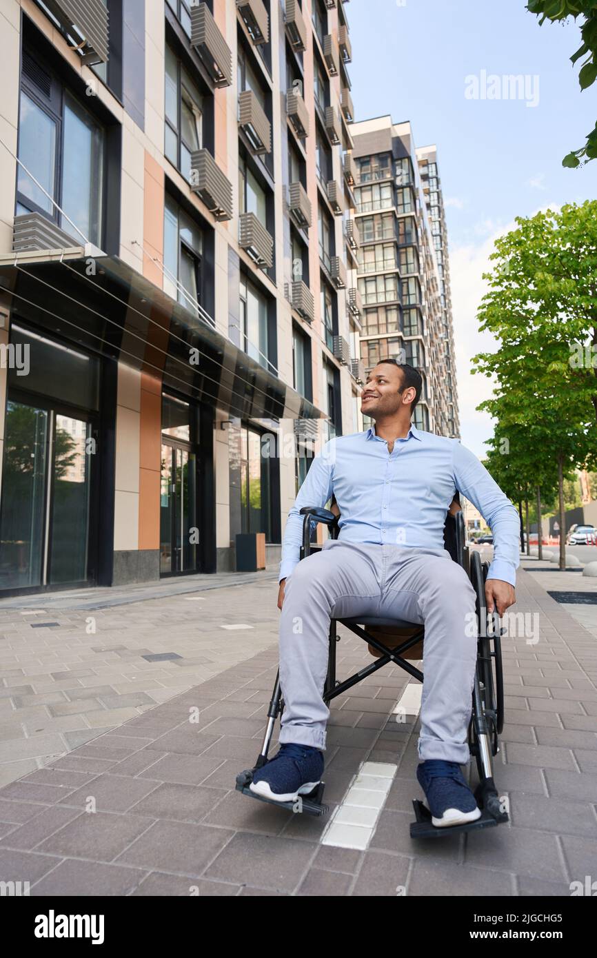 Disabled person moving in wheelchair on sidewalk Stock Photo - Alamy