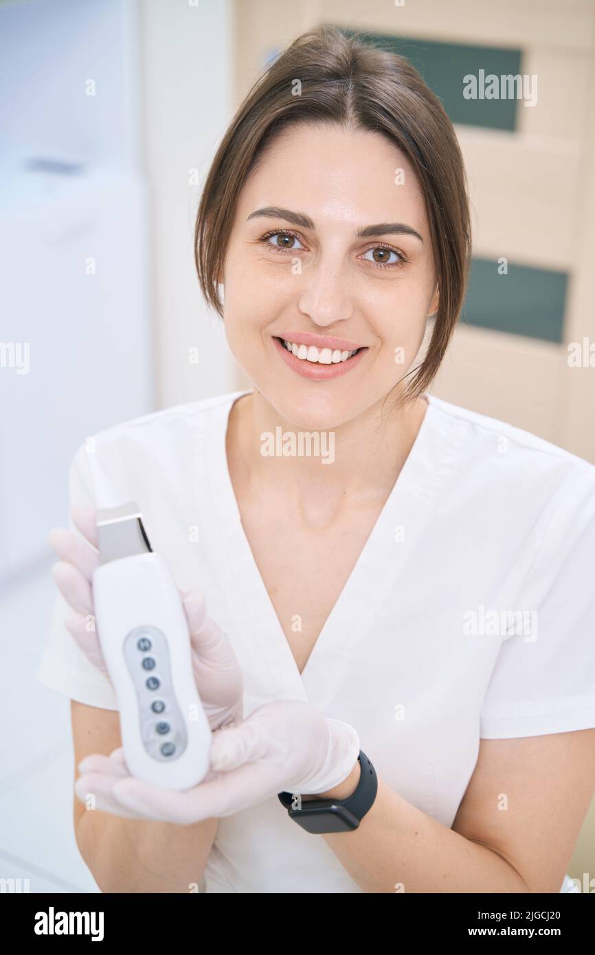 Doctor cosmetologist holds an ultrasonic apparatus for cleaning facial ...