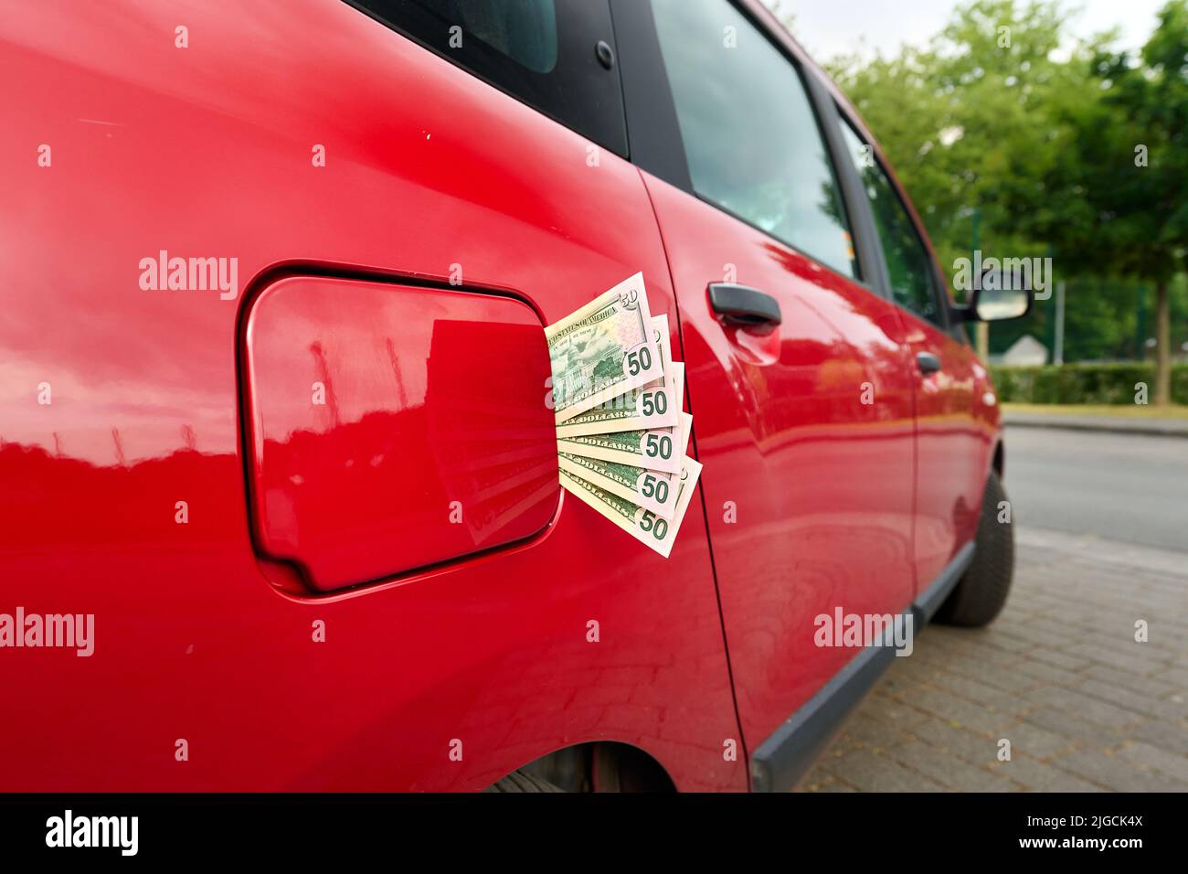 Symbol for high fuel price - Fifty dollar bills sticking out of a car's ...