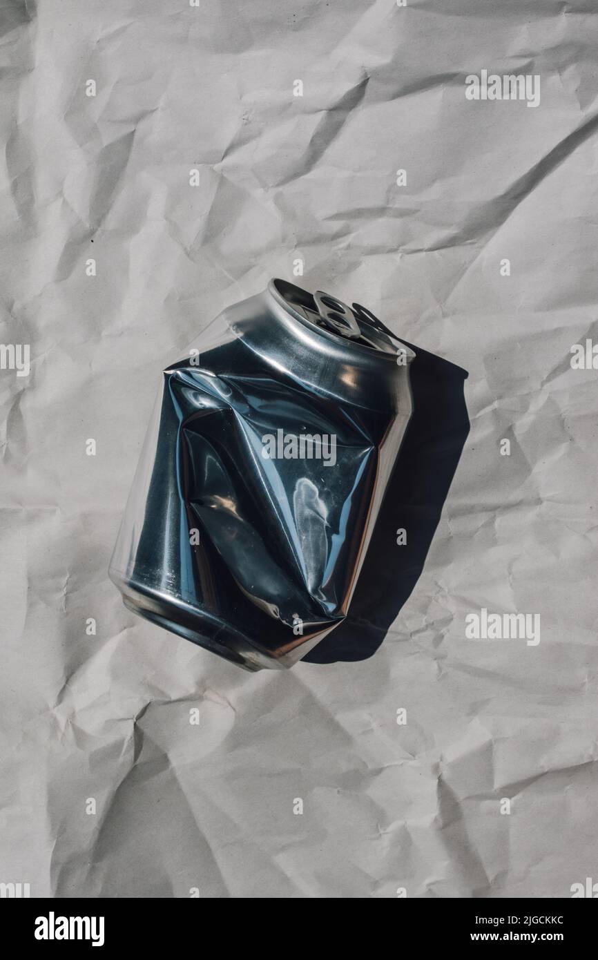 crumpled paper with hand shadow and crumbled crushed aluminum can ...