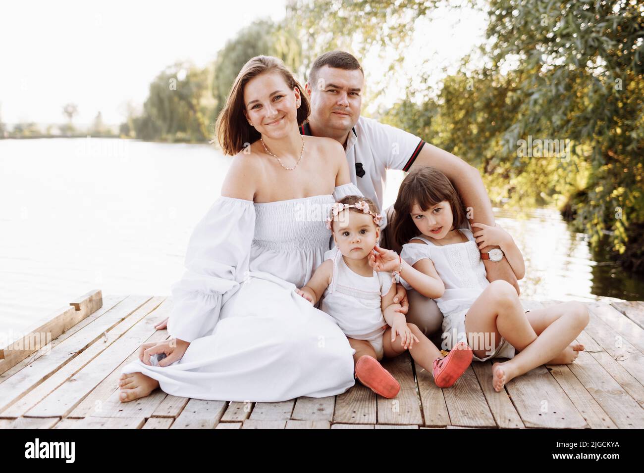 Happy young family near lake, pond on summer. Mother, father and two ...