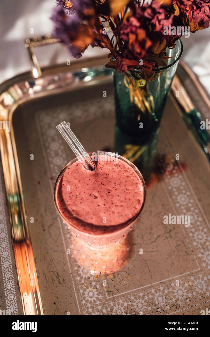 mixed berry smoothie with glass straw on silver breakfast tray with ...