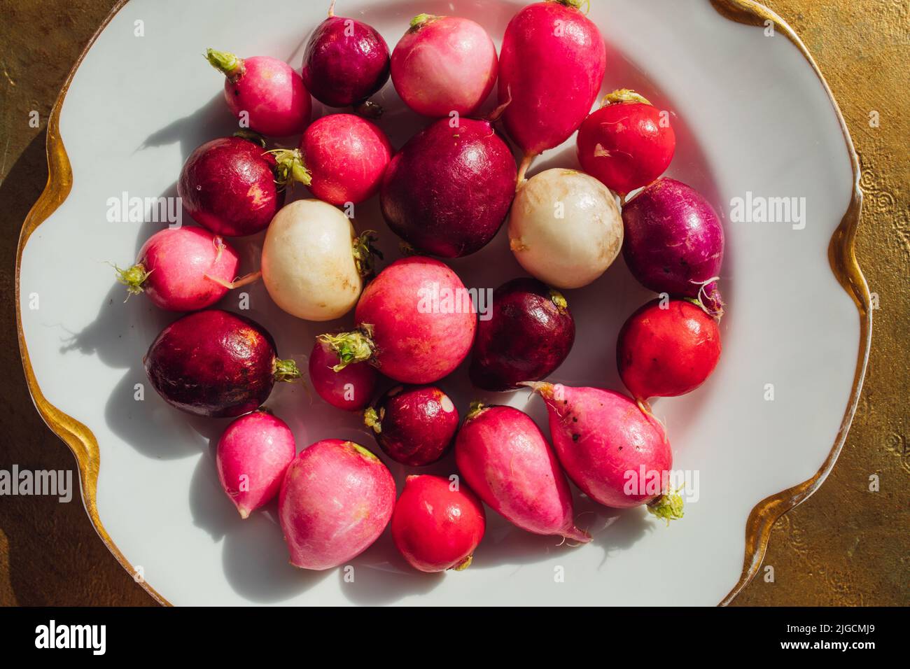 trimmed pink, red, purple, white radishes on white plate with gold ...