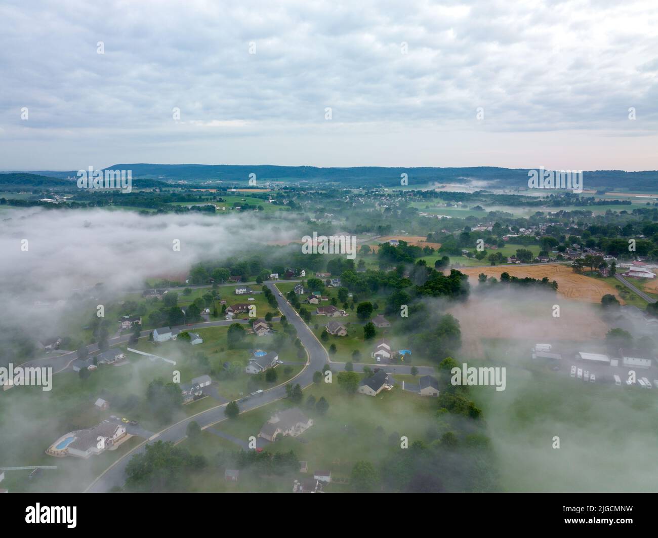 An aerial view from above the fog as it covers the landscape, fields ...